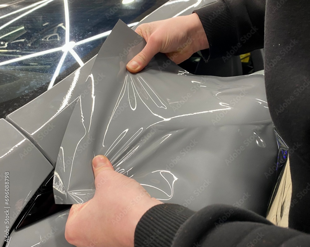 The process of wrapping vinyl film on the side mirror of a car in close ...