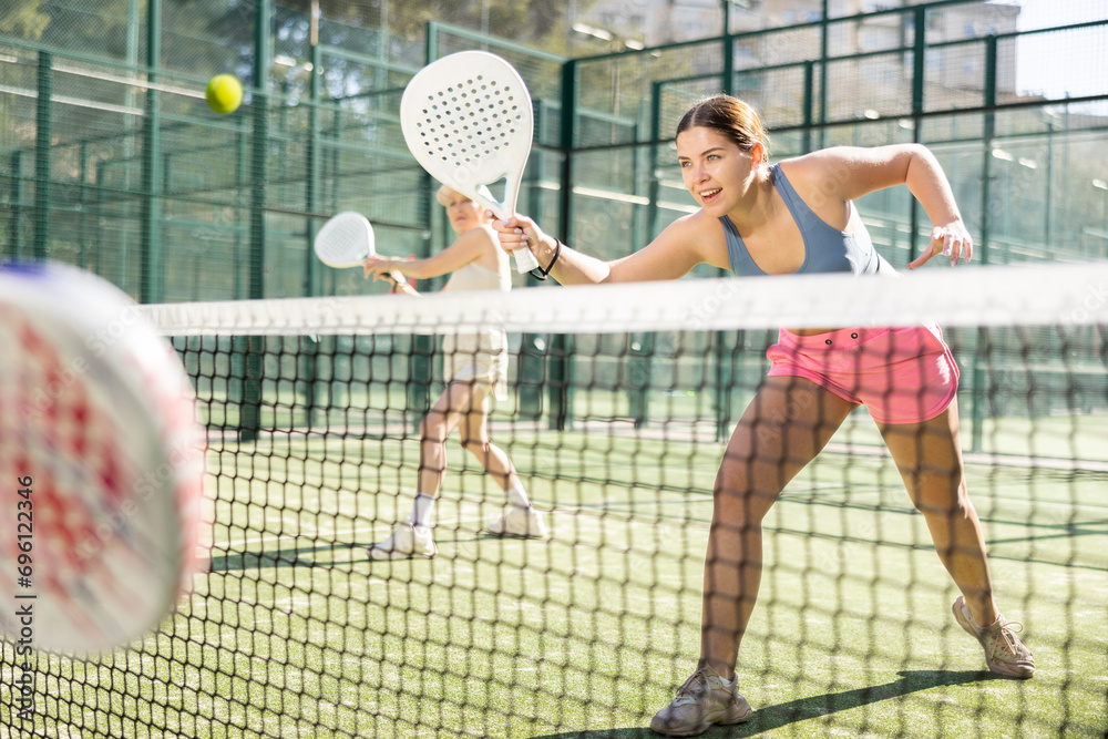 Foto de Dynamic young woman playing Padel Tennis with partner in the ...