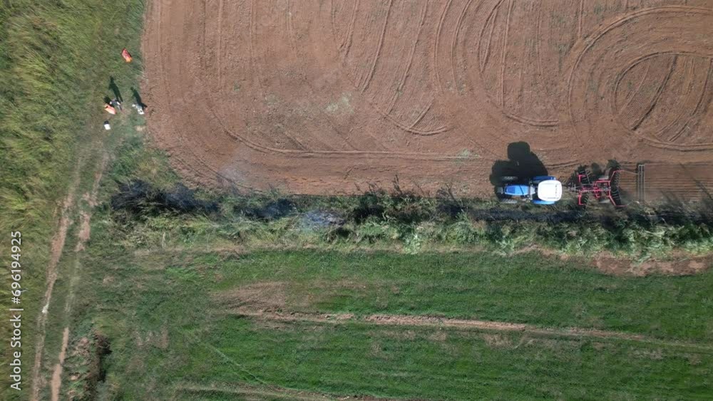 Shooting from drone flying over tractor with harrow system plowing ...