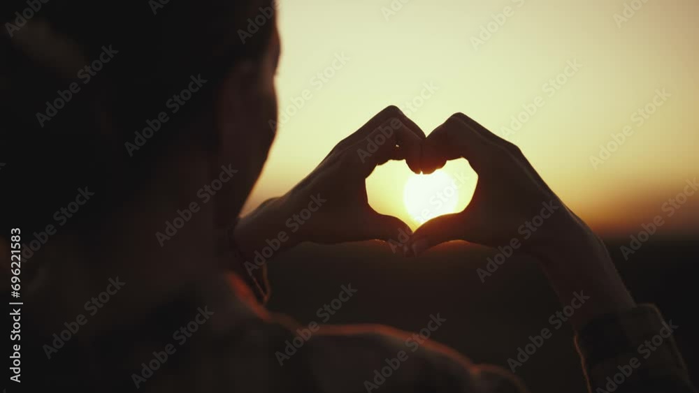 Woman folding hands at sunset in heart shape, symbol of real romantic ...