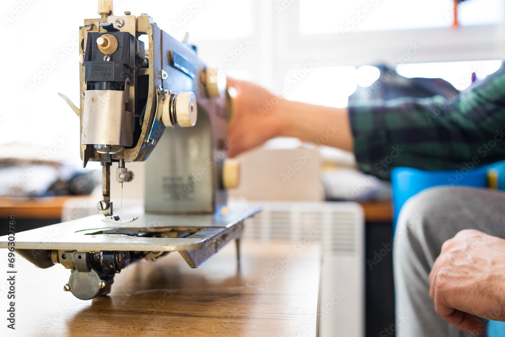 Repairman master is testing old disassembles sewing machine in workshop ...