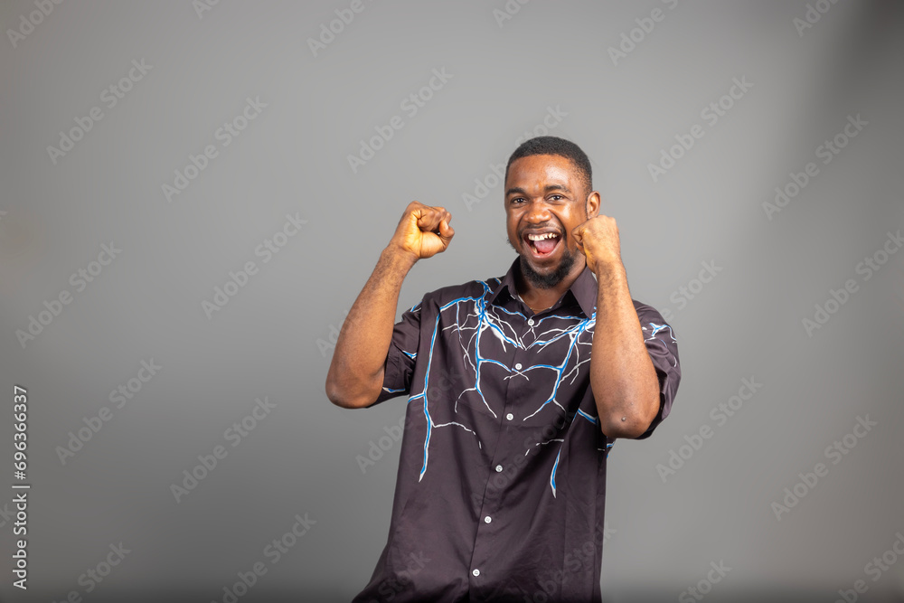 Overexcited young black guy raising fist up on white background ...