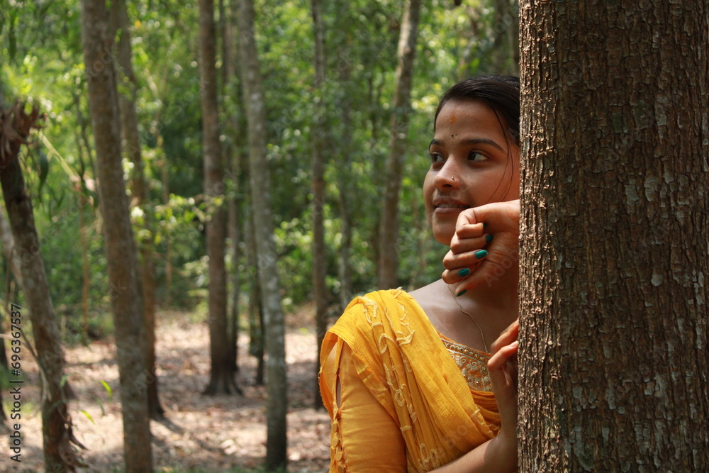 Young Indian girl hiding behind the tree. Portrait of young Indian girl ...