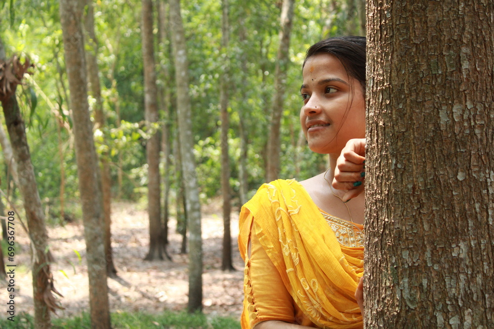Young Indian girl hiding behind the tree. Portrait of young Indian girl ...