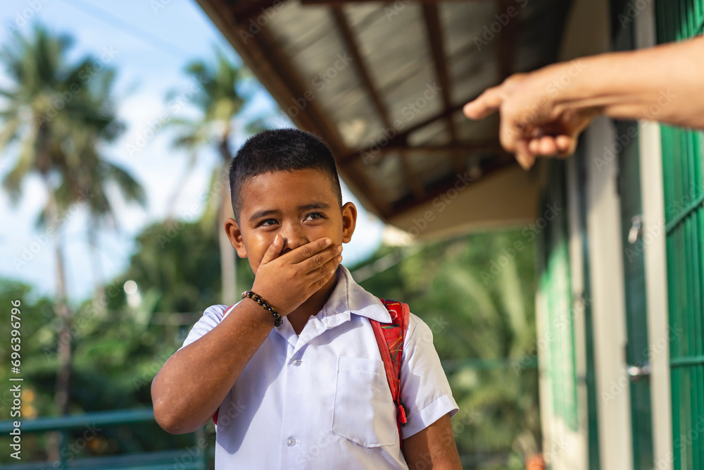A young elementary student feels embarrassed after being scolded by an ...