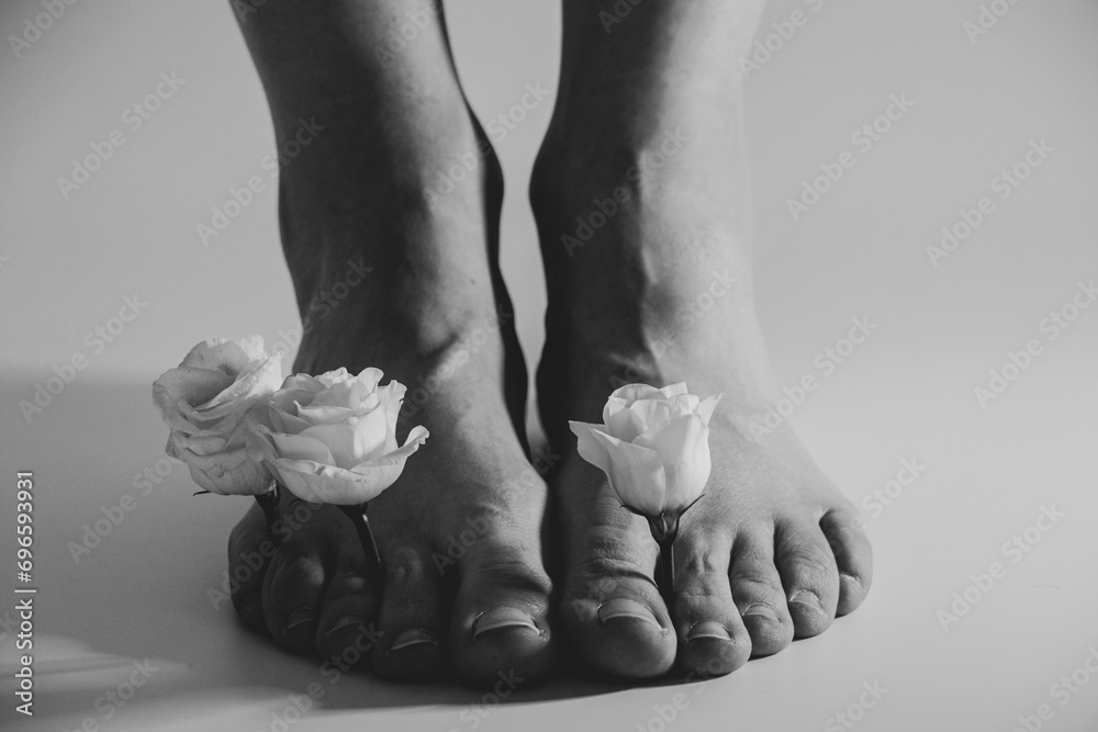Three small white flowers stick out between the toes of a woman's feet ...