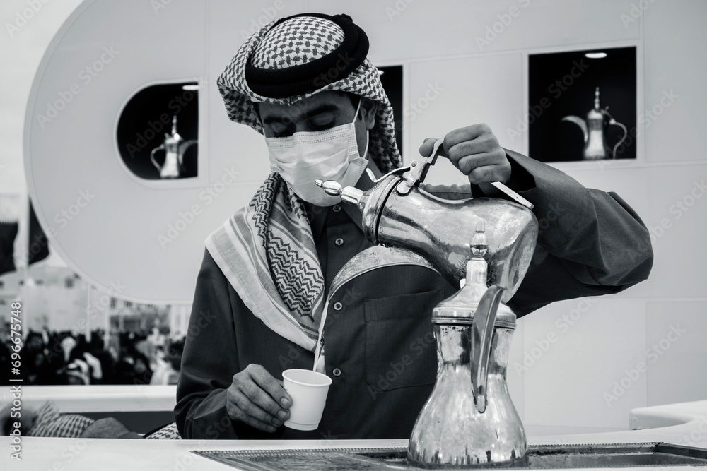 Black and wite photo for A young Qatari Arab in traditional dress pours ...