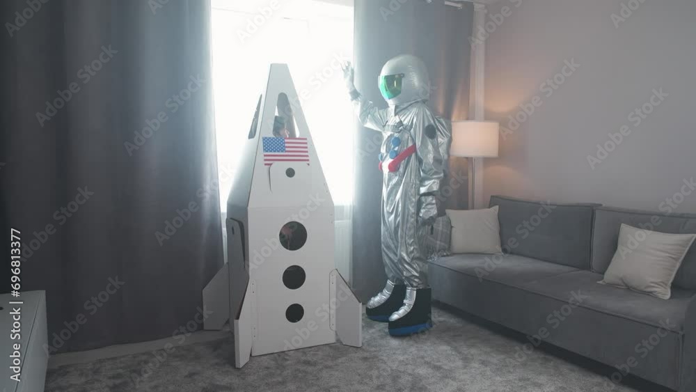 Father and son play in the living room at home, father in an astronaut ...
