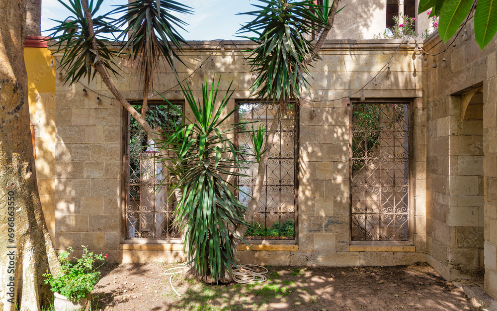 Verdant palm trees rises alongside a weathered aged stone wall, with ...
