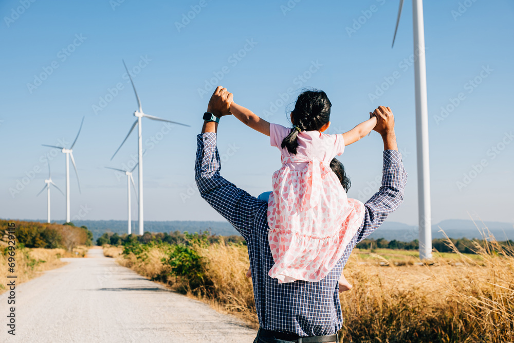 Father joyfully carries daughter exploring wind farm. Family bonding ...