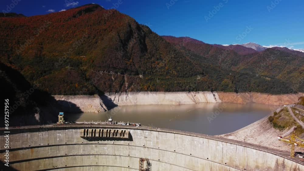 High concrete arch dam holding river located among green mountains ...