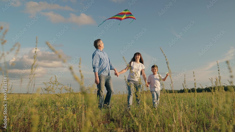 Young family is playing with kite in meadow. Active people together ...