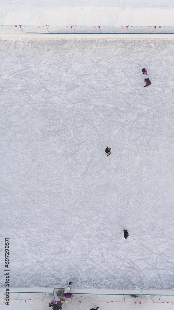 People are skating on ice rink in the sunny day. Aerial vertical top ...