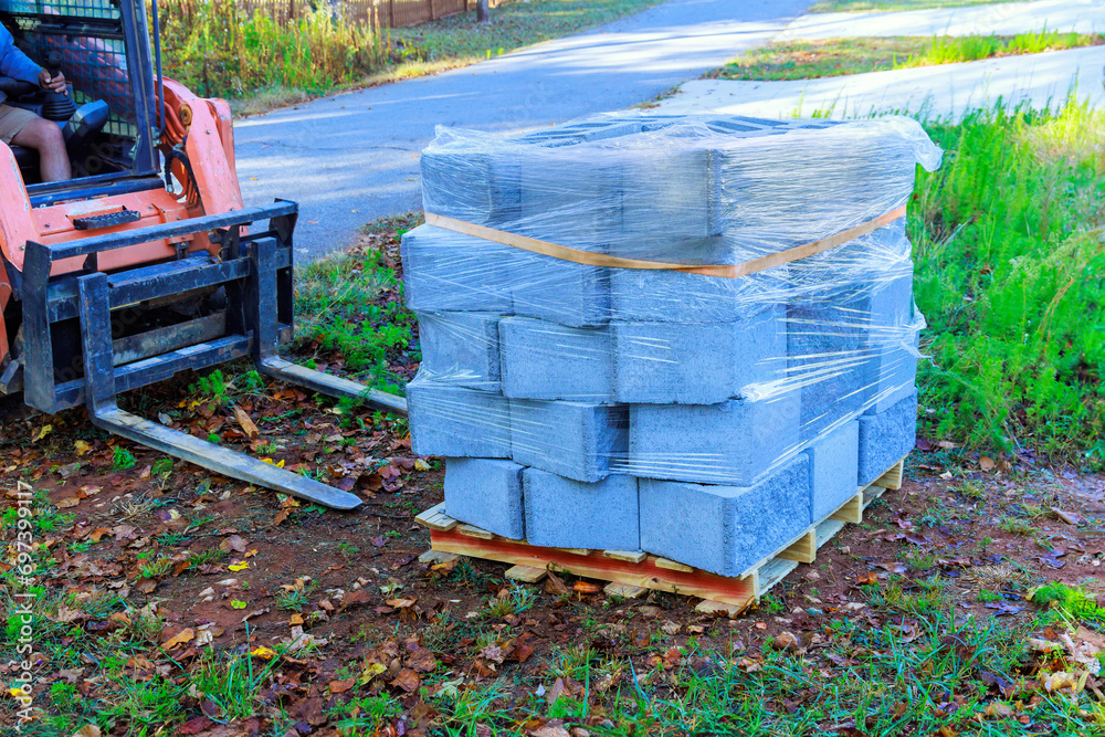 Worker at small forklift unloading lifts pallet concrete blocks for ...