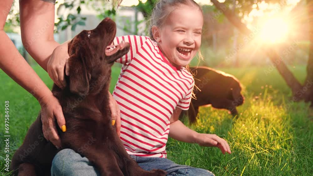 Little girl plays with puppies with her mother in park. Child, mom ...