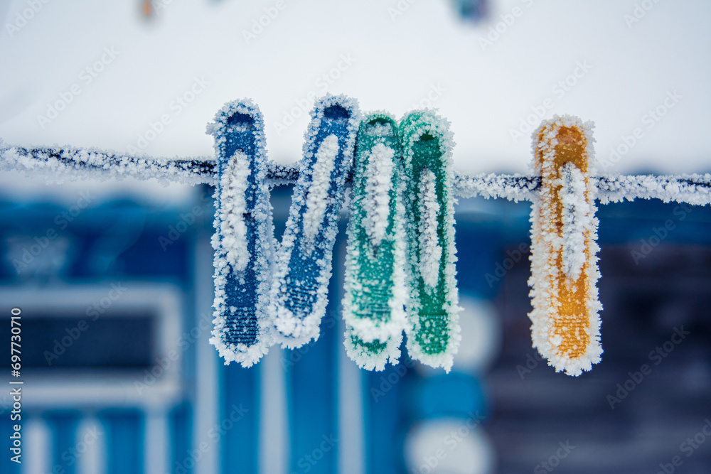 clothespins hanging on a clothesline covered with snow frozen under ice ...