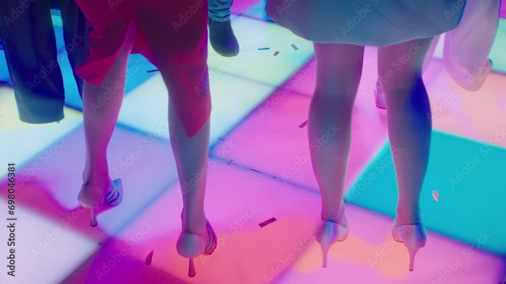 Slender female legs in high-heeled shoes dance on luminous square disco ...