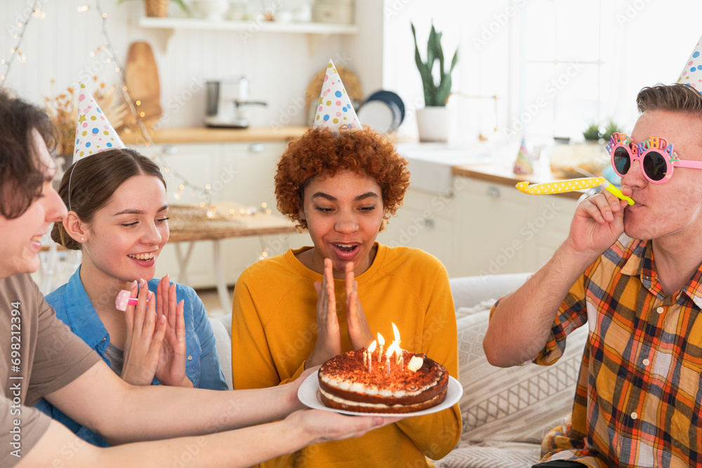 Make a wish. Woman wearing party cap blowing out burning candles on ...