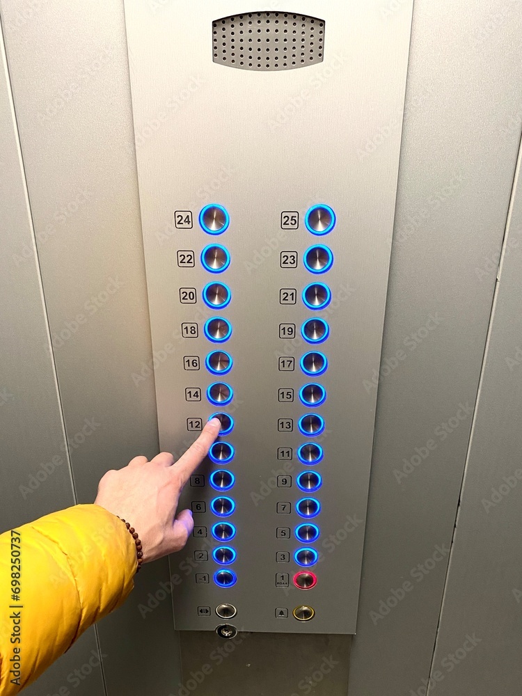 Hand reaching for pressing a button in an elevator, inside an elevator ...