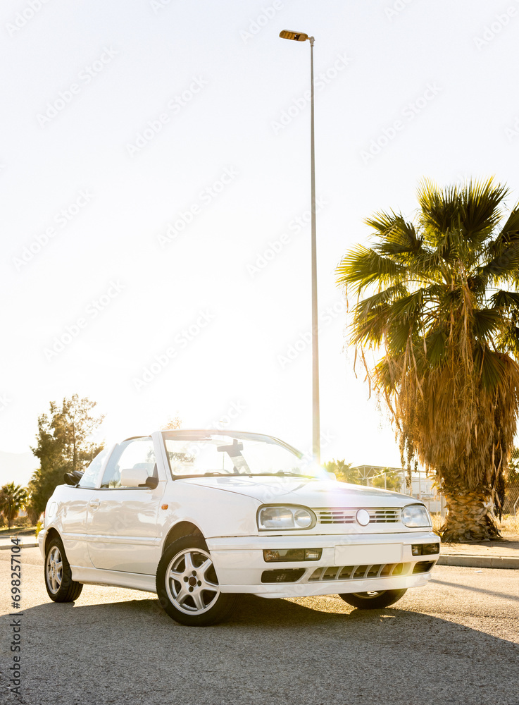 Vertical photo of a white 1996 convertible at sunset. Old car without a ...