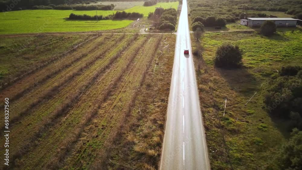 Drone footage of a care driving on an asphalt road passing through ...