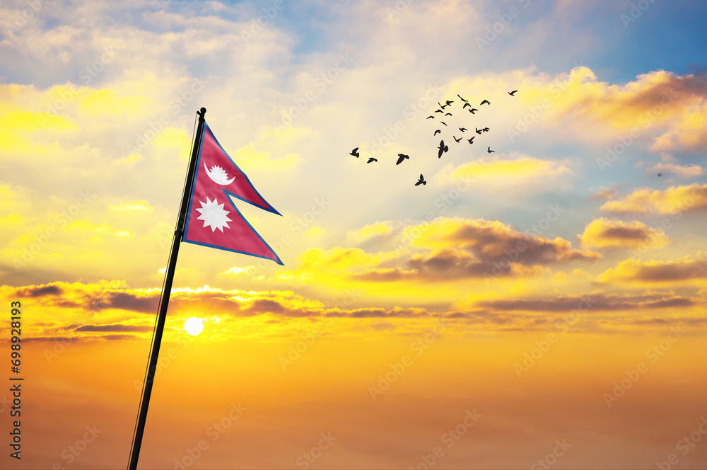 Waving flag of Nepal against the background of a sunset or sunrise ...