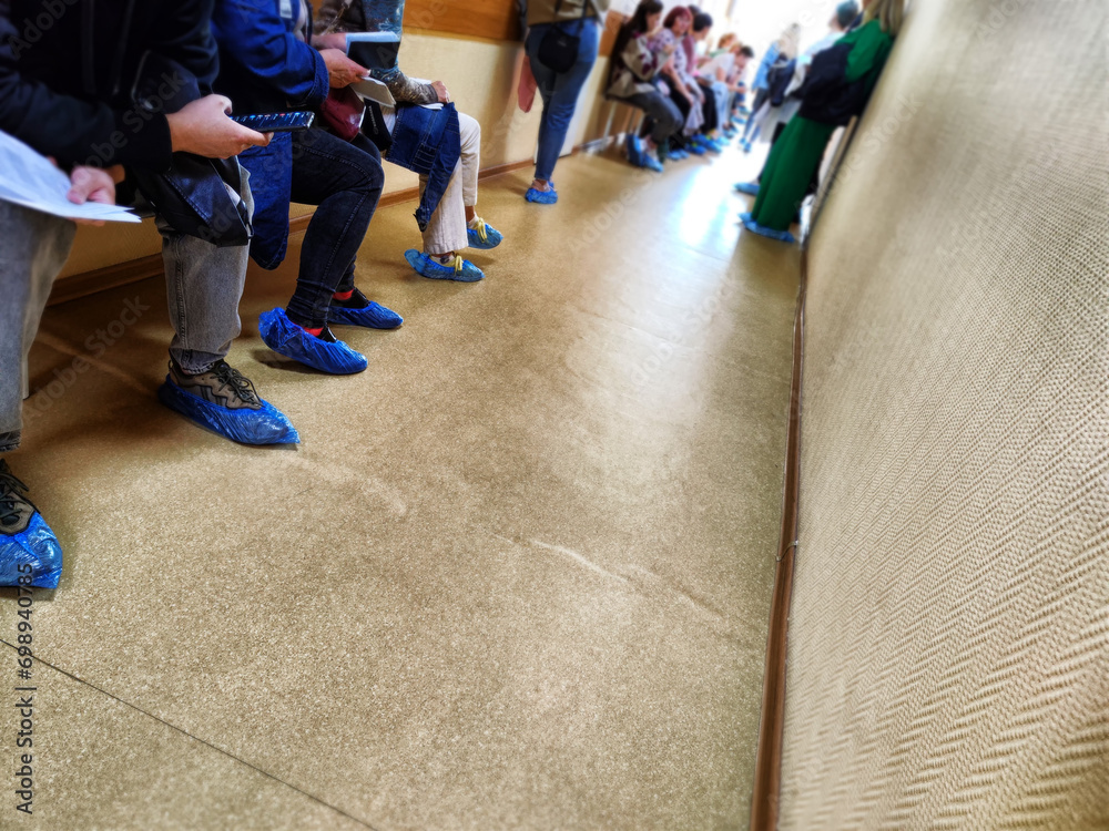 People are sitting in the hallway at the hospital waiting for a visit ...