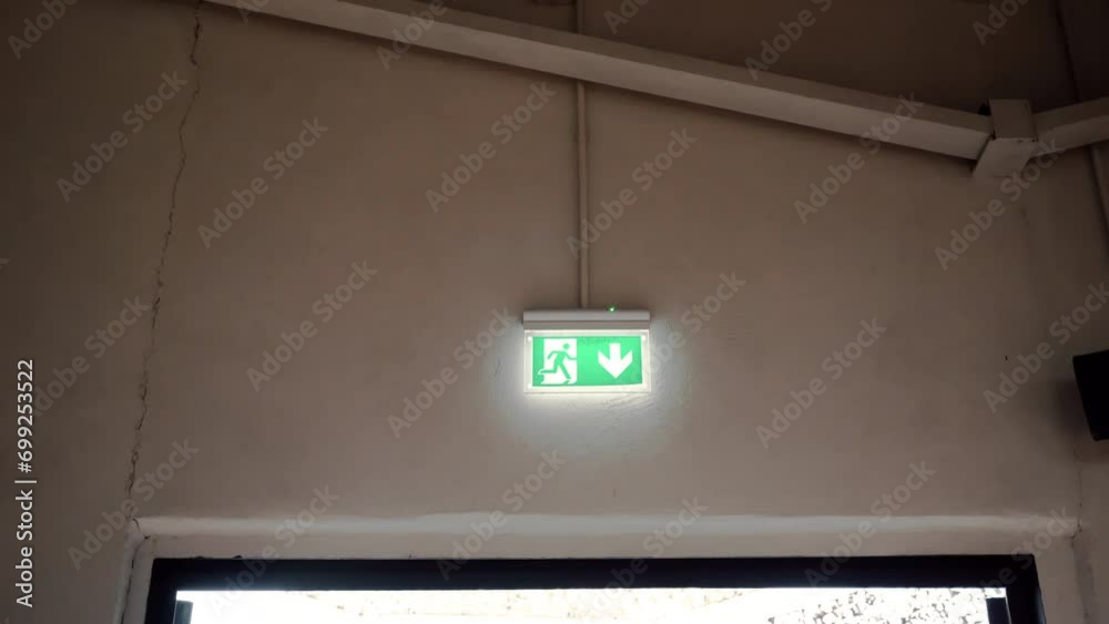 Green emergency exit sign on the wall above the door, down arrow and ...