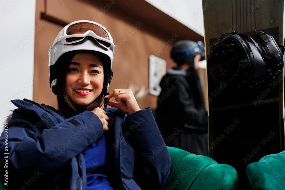 Female asian traveler sits on hotel lobby couch, wearing winter jacket ...