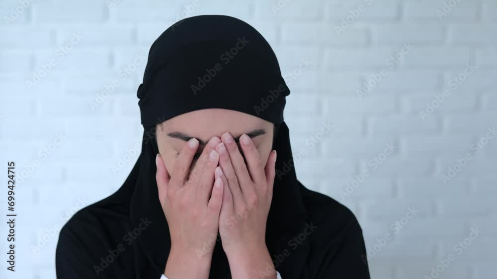 Muslim woman in black hijab covered face with hands. Close-up shot ...