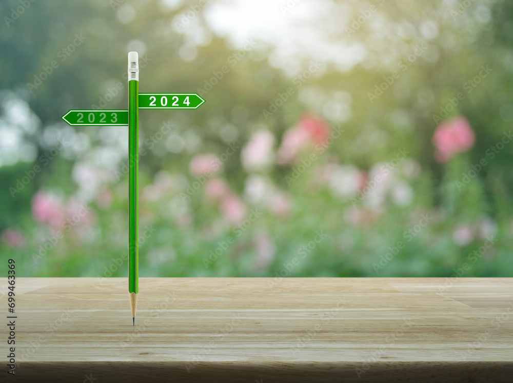 2024 and 2023 direction sign plate with green pencil on wooden table ...