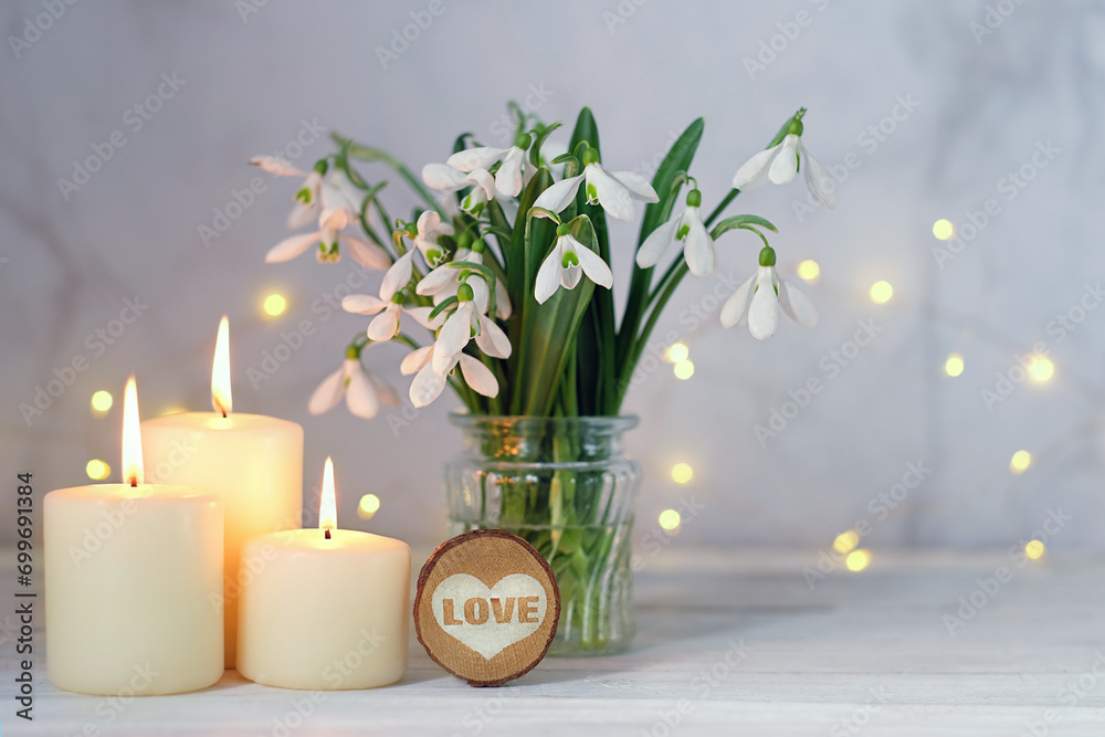 Bouquet of Snowdrop flowers , heart decor and burning candles on table ...