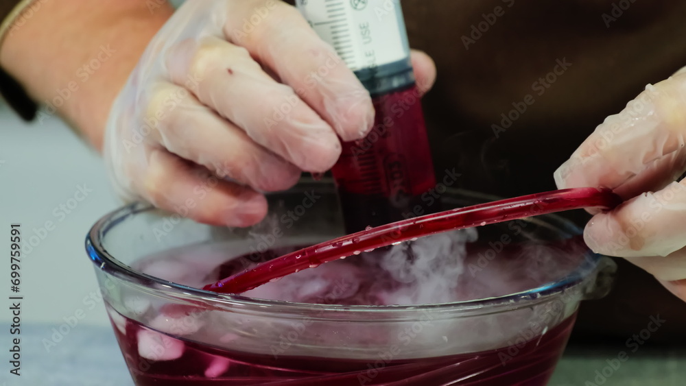 Male cook holds syringe with silicone tube filled with agar solution ...