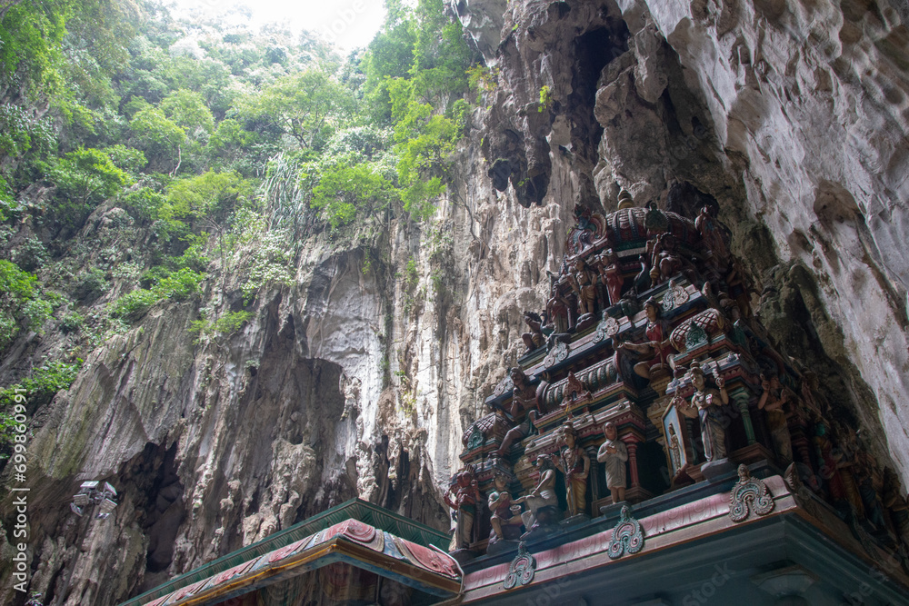 Ancient temple entrance carved into a limestone cave surrounded by lush ...