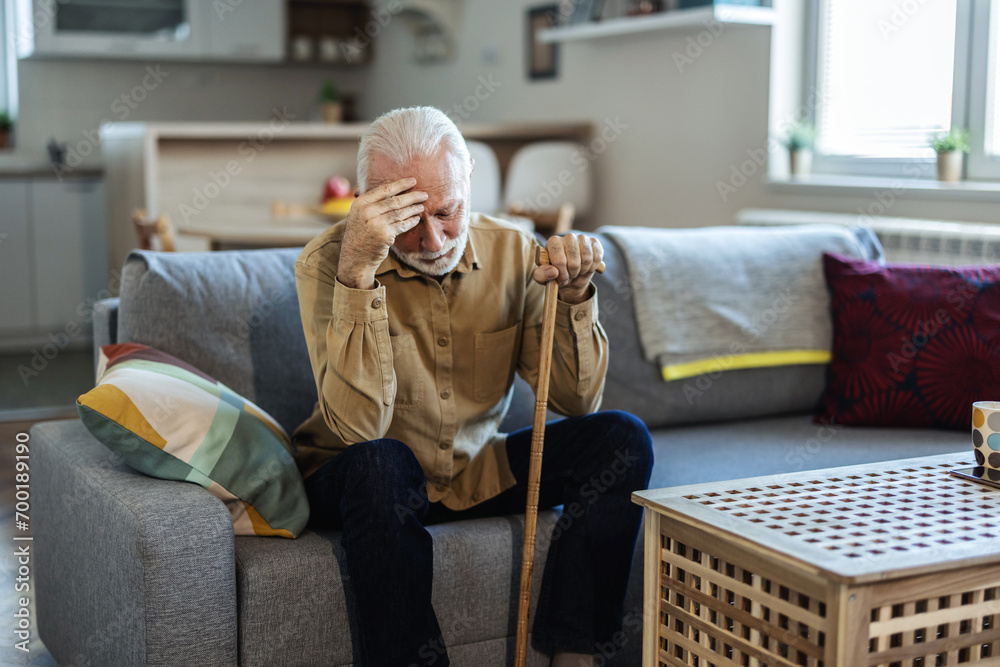 Depressed old man sitting at home while holding walking stick. Retired ...