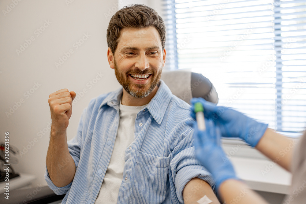 Happy man gives blood for tests in laboratory, medical worker holds ...