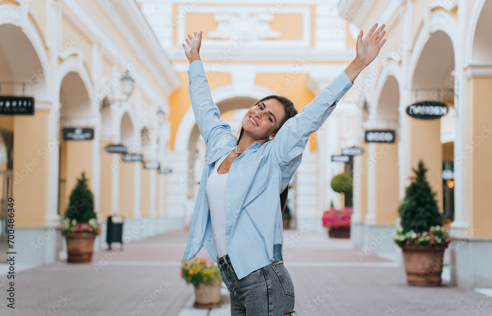 Exuberant woman with arms raised in celebration, wearing a chic outfit ...