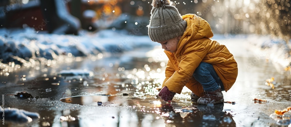 Happy young girl playing with thin ice puddles formed on the frozen ...