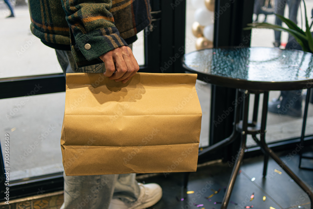 A man holds a paper bag in his hand. Food delivery. Courier with a ...
