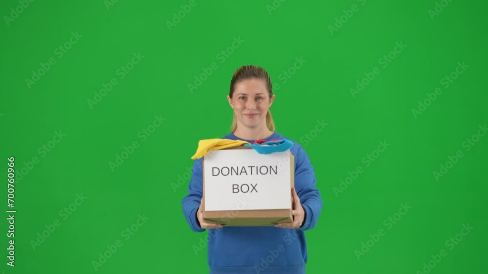 A woman volunteer holds a box full of clothes labeled Donation box. The ...
