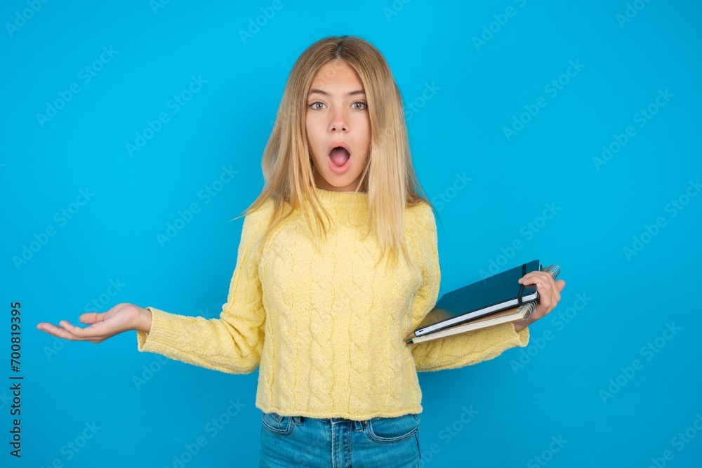 Frustrated Beautiful kid girl wearing yellow sweater holding notebook ...