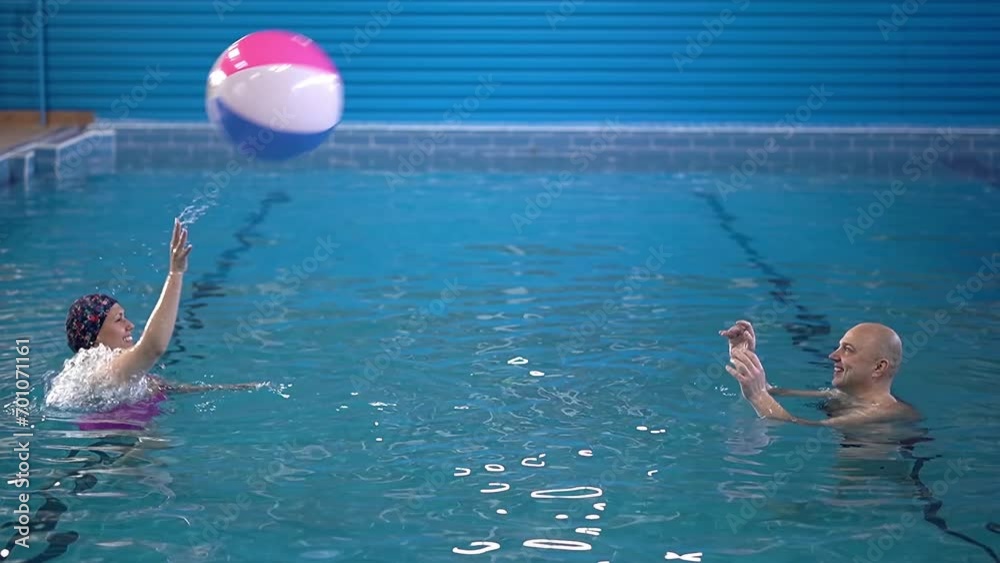 training for adults. woman and man in the pool. throwing the ball to ...