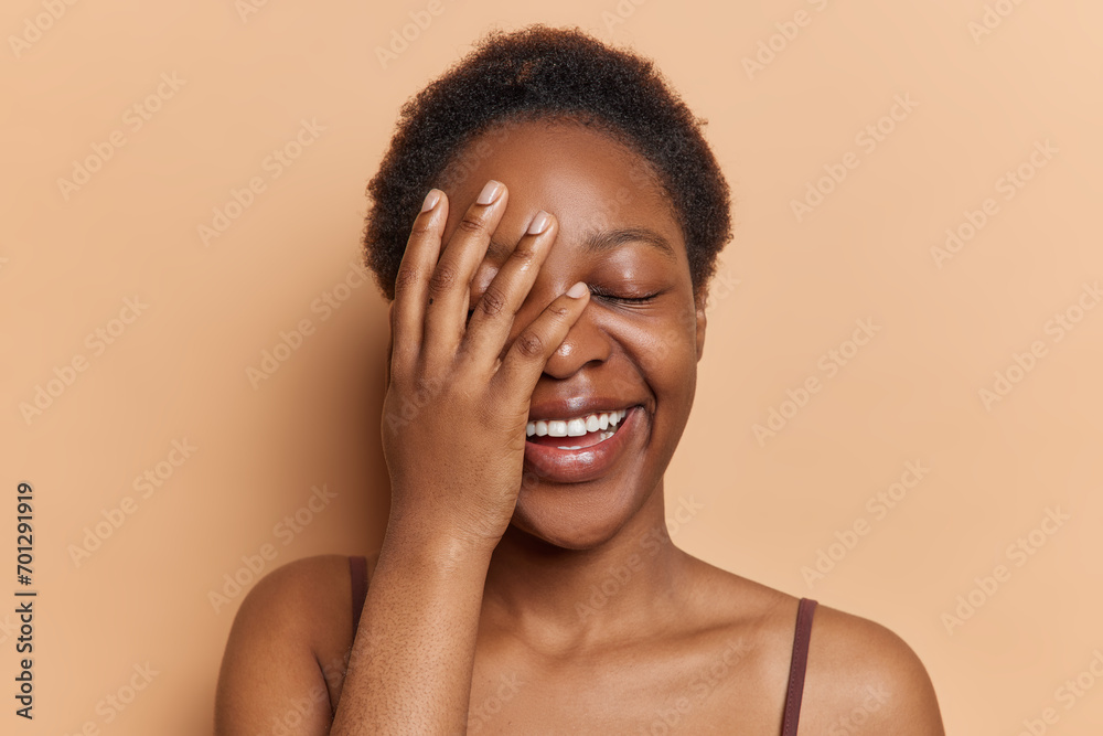 Horizontal shot of happy dark skinned African woman with curly short ...