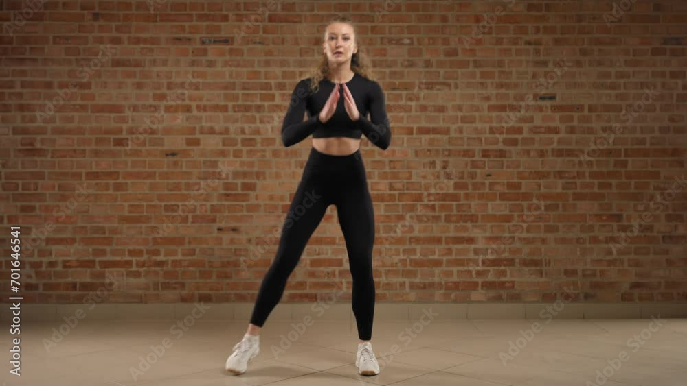 A young female trainer conducting a sports video lesson. She performs ...