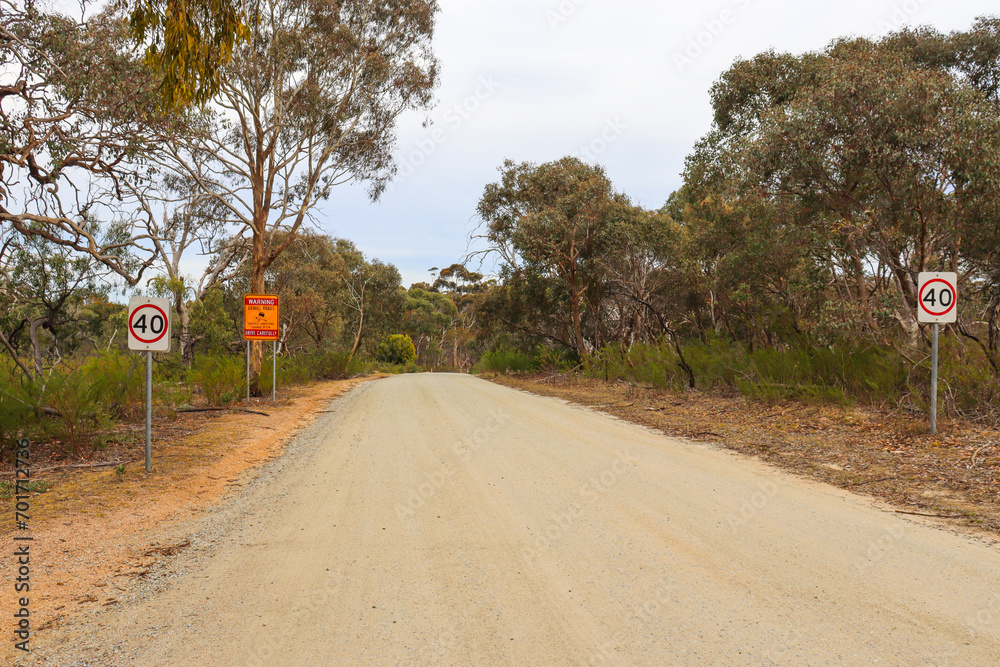 dirt road through australian bushland with speed limit and gravel road ...
