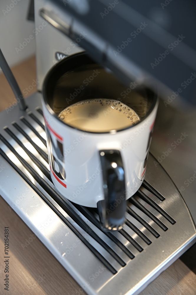 Coffee mug with coffee crema under the outlet of a fully automatic ...