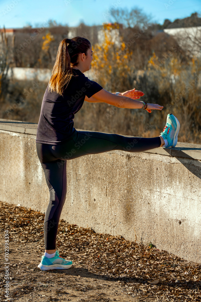 Young runner, dressed in tight black sports clothing and hair tied in a ...