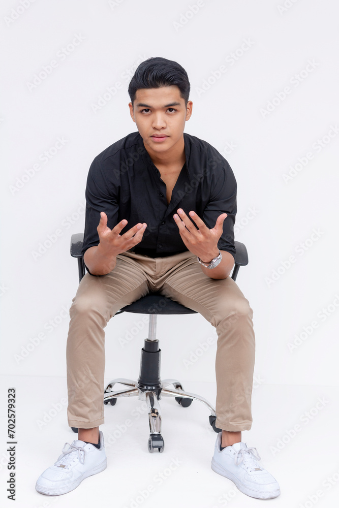 A young asian man leaning forward on his chair and giving a detailed in ...