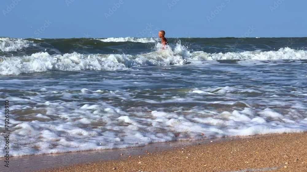 A child swims in the Sea of Azov. A boy jumps into the sea waves from ...