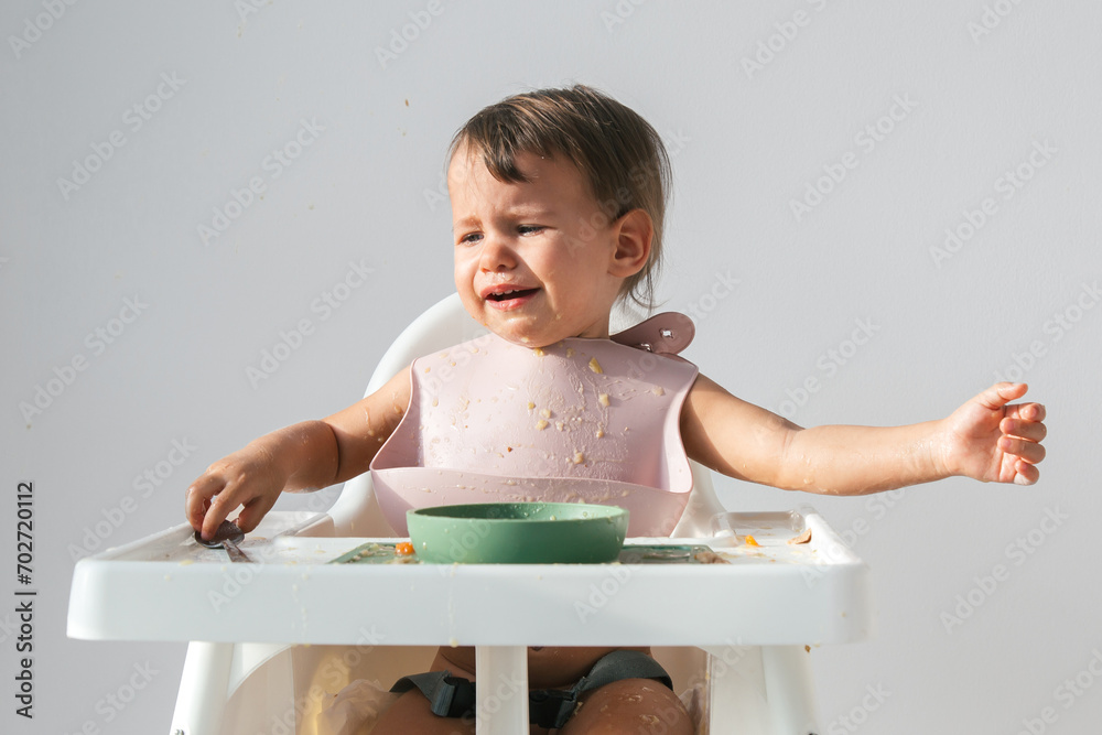 cute crying baby sitting eating lunch in high chair at home on white ...